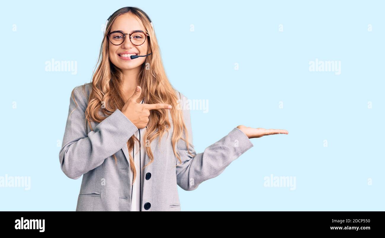 Young beautiful blonde woman wearing call center agent headset amazed ...
