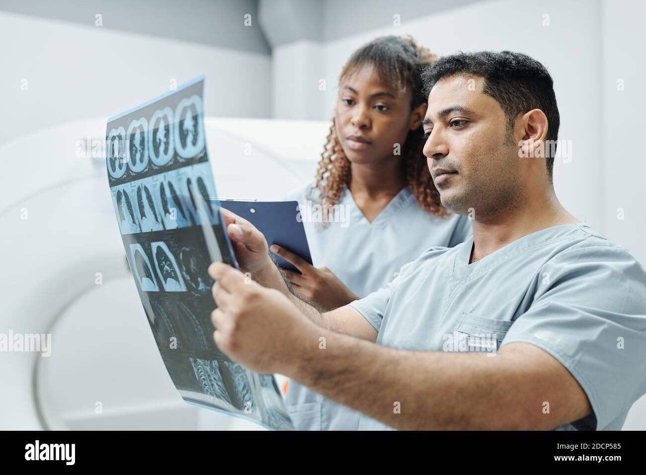Mixed-race radiologist and his African female assistant analyzing x-ray ...