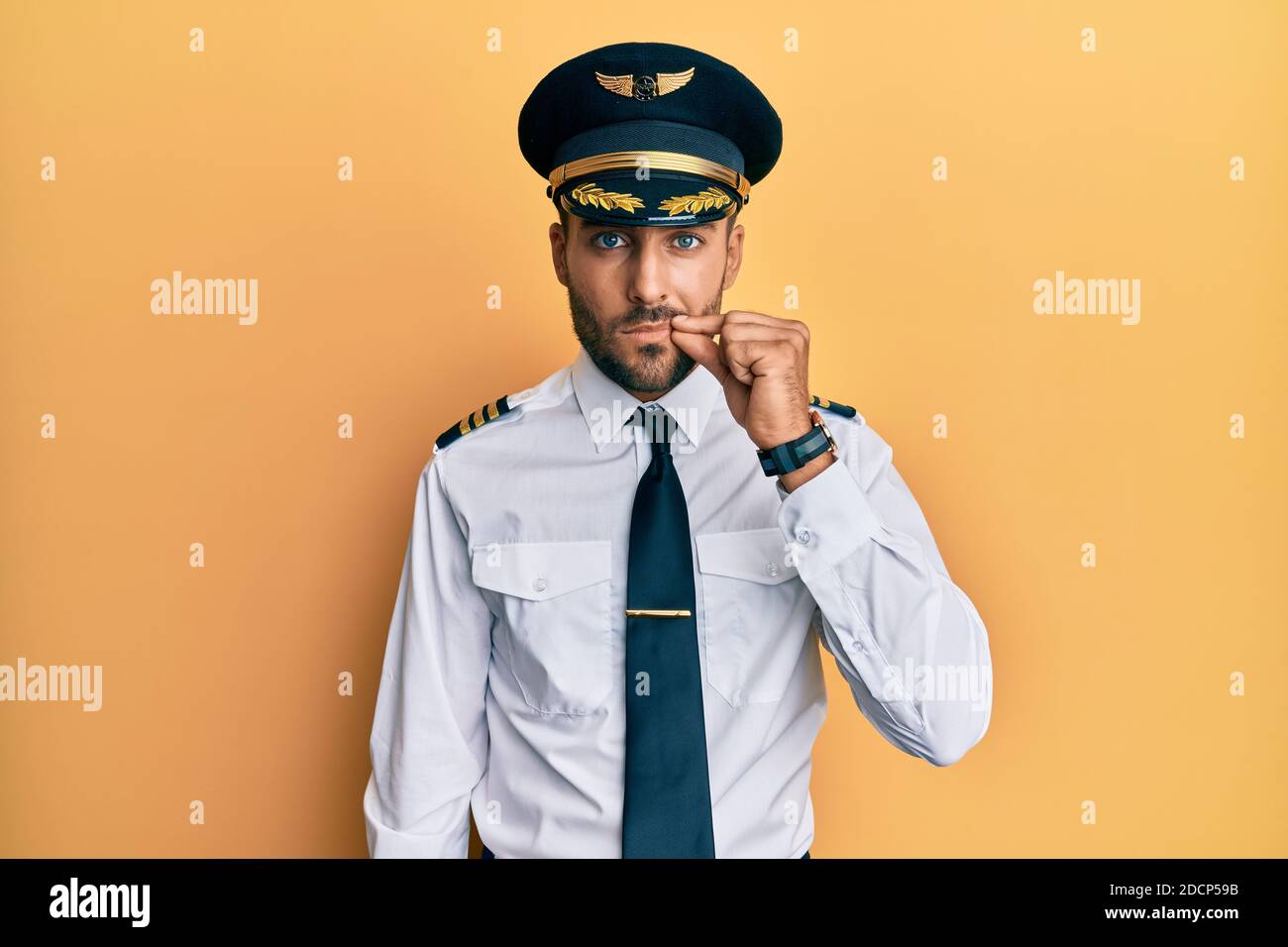 Handsome hispanic man wearing airplane pilot uniform mouth and lips ...