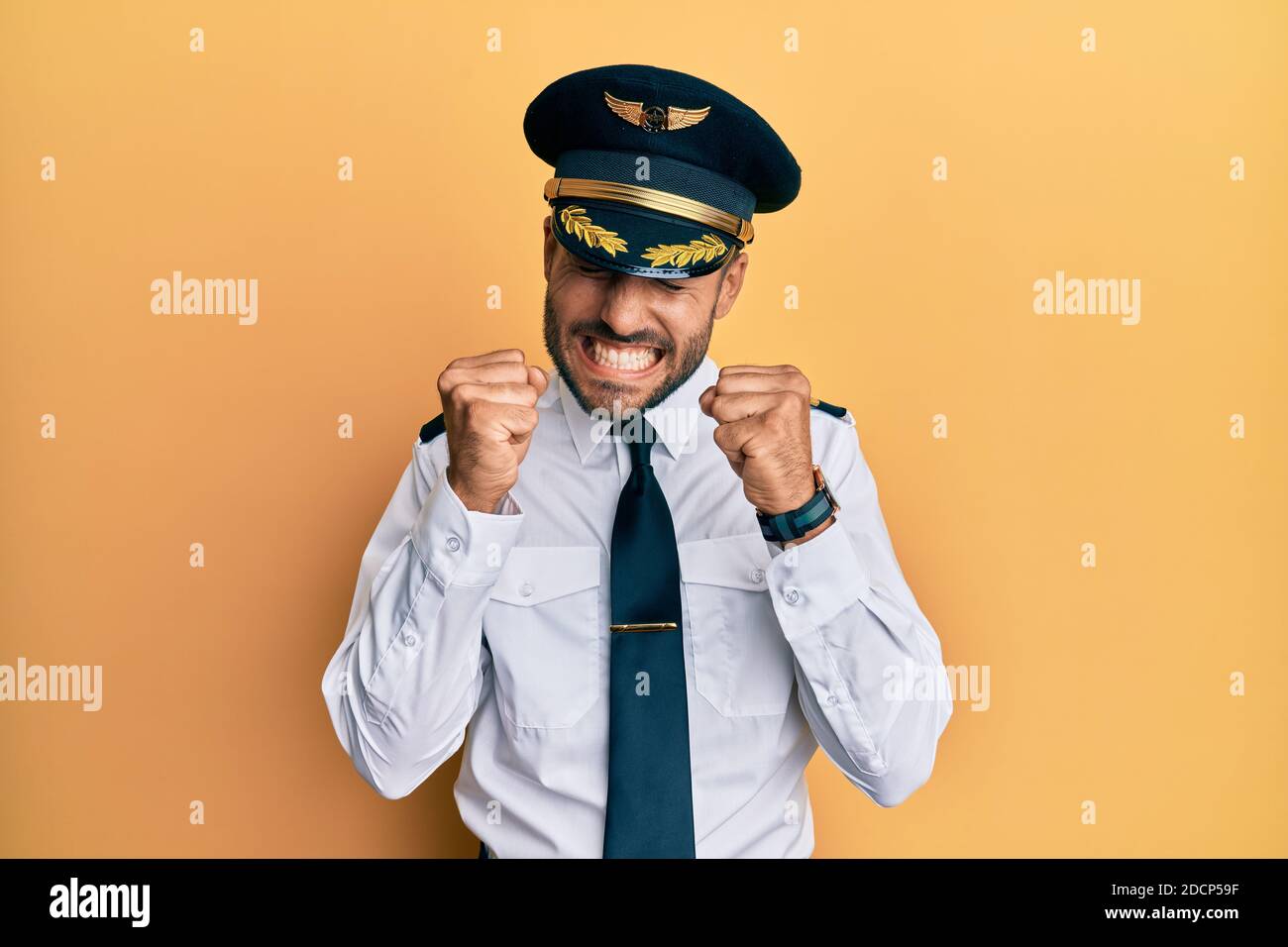 Handsome hispanic man wearing airplane pilot uniform excited for ...