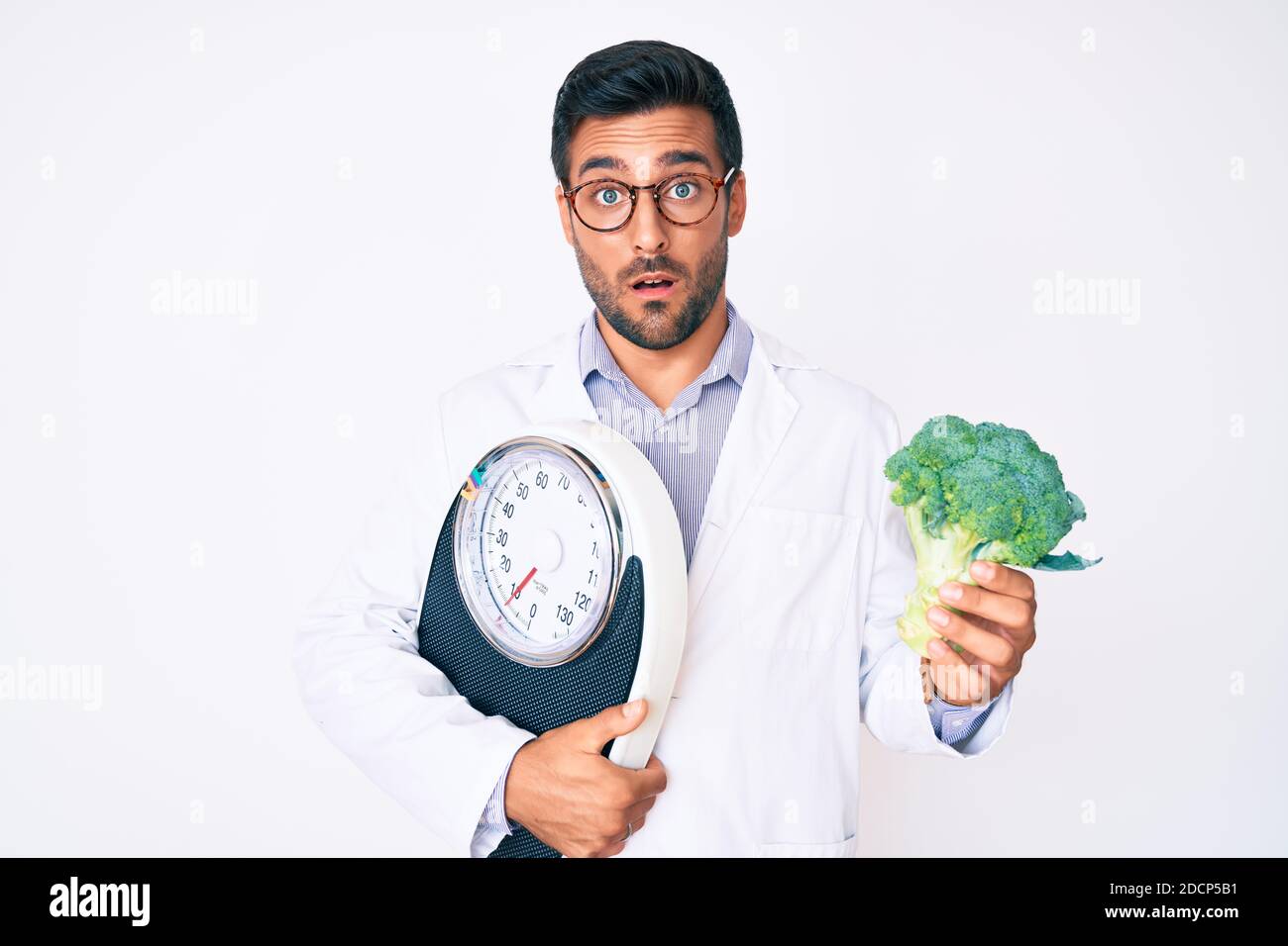 Young hispanic man as nutritionist doctor holding weighing machine and ...