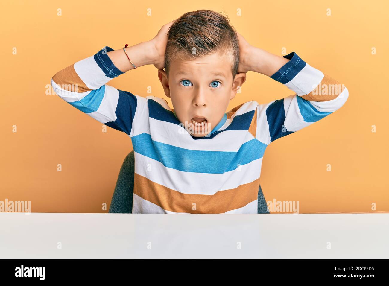 Adorable caucasian kid wearing casual clothes sitting on the table ...