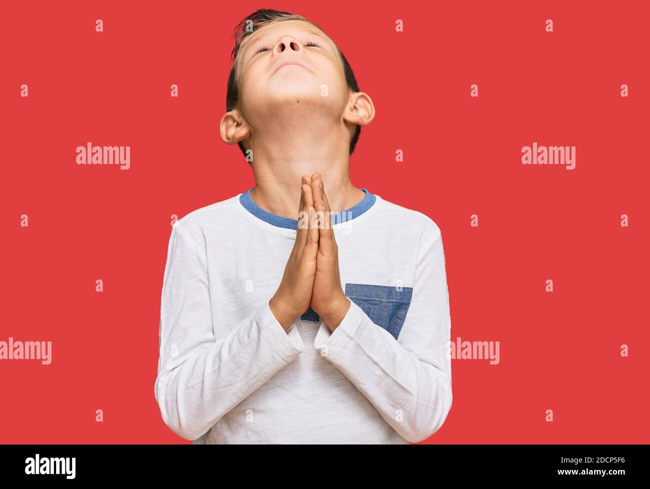 Adorable caucasian kid wearing casual clothes begging and praying with ...