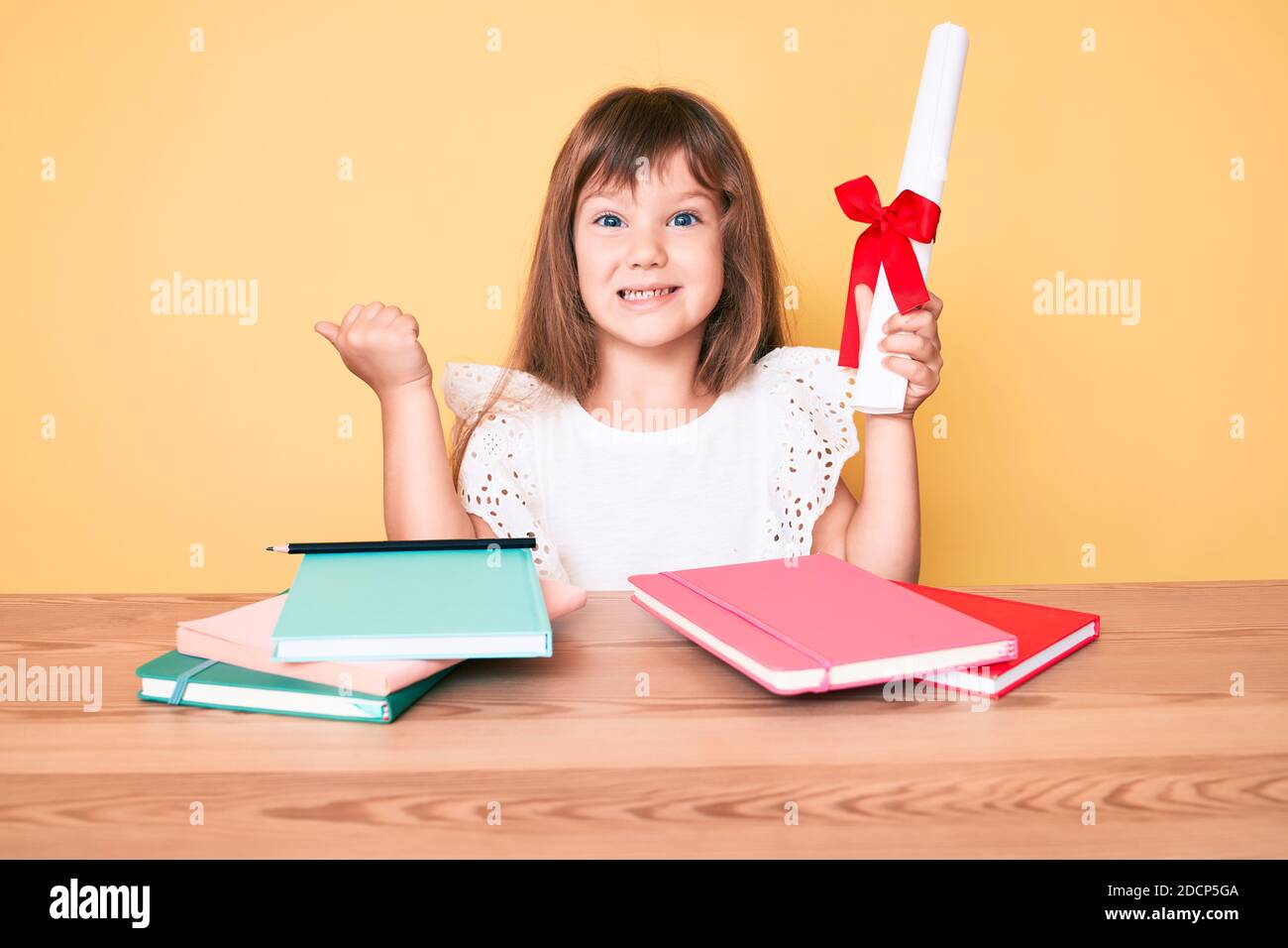 Little caucasian kid girl with long hair holding graduate degree ...