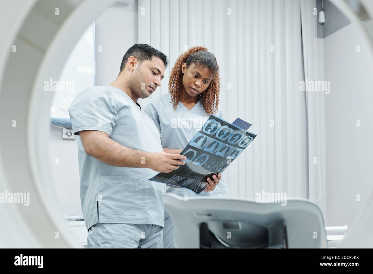 Serious male radiologist and his assistant in uniform analyzing x-ray ...