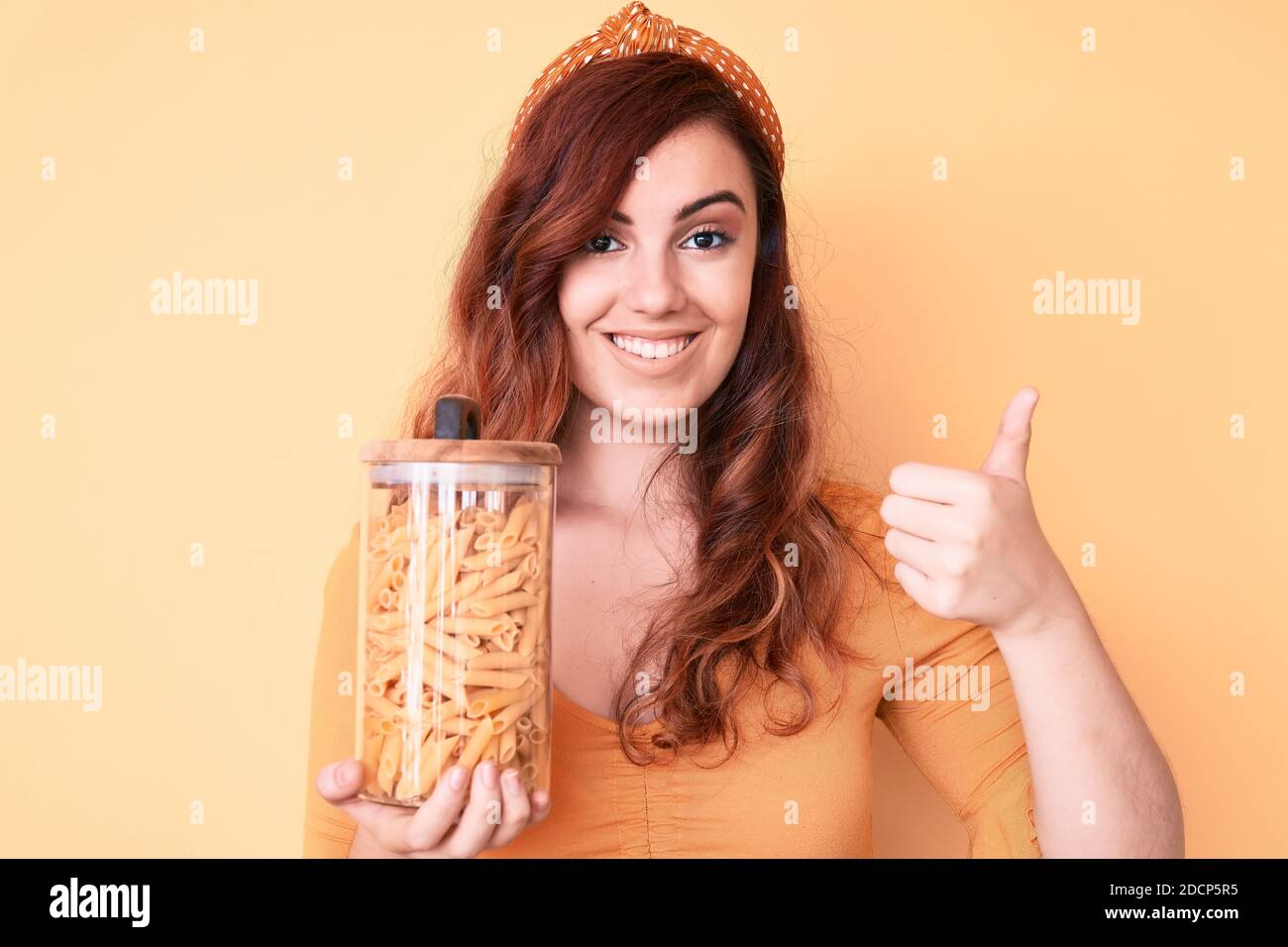 Young beautiful woman holding jar of macaroni pasta smiling happy and ...