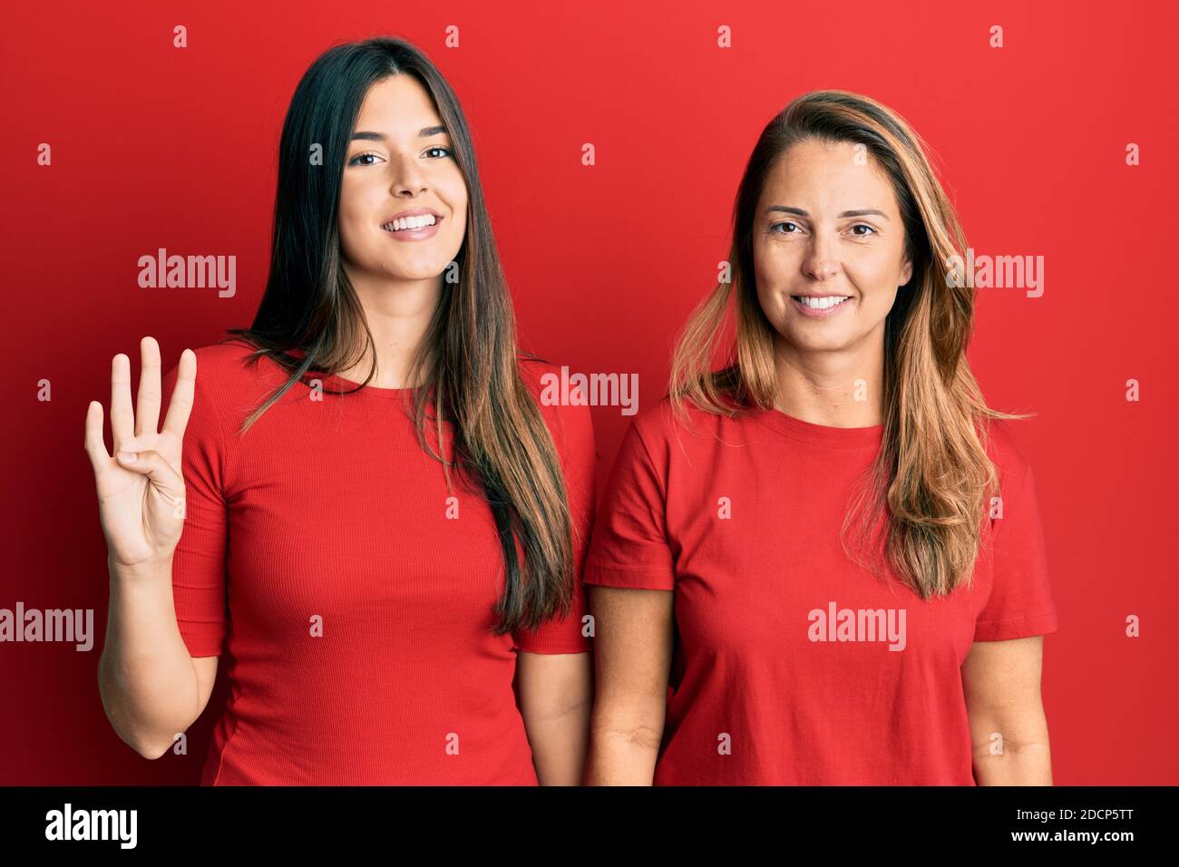 Hispanic family of mother and daughter wearing casual clothes over red ...