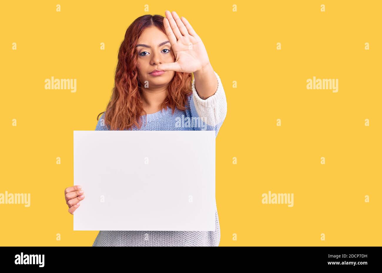 Young latin woman holding blank empty banner with open hand doing stop ...