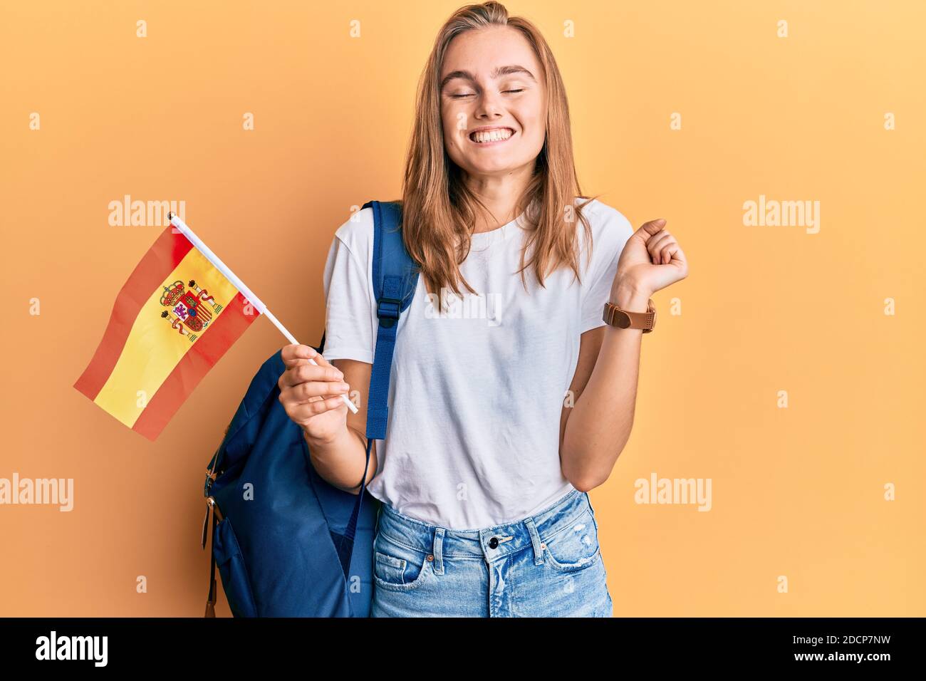 Beautiful blonde woman exchange student holding spanish flag screaming ...