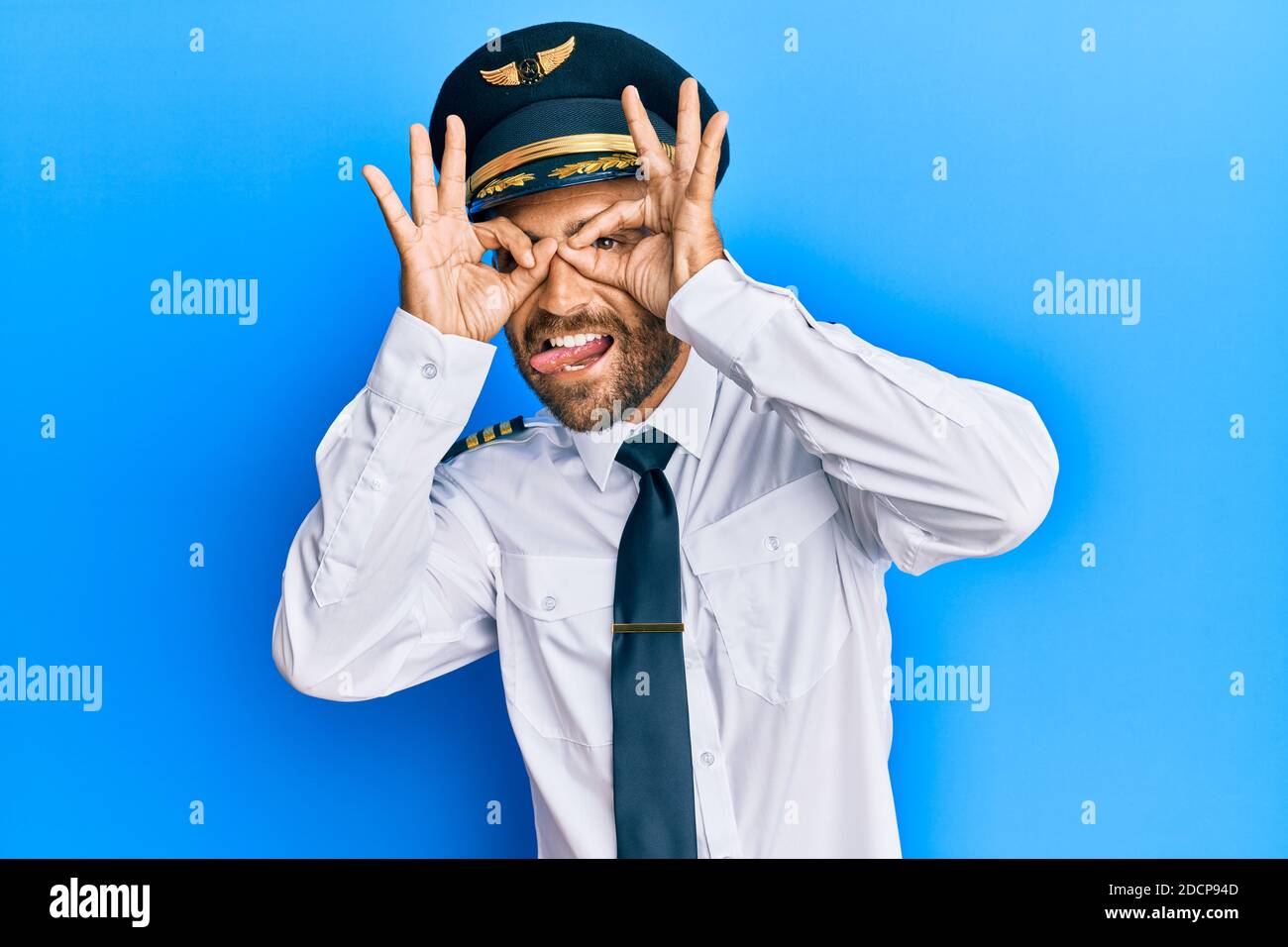 Handsome man with beard wearing airplane pilot uniform doing ok gesture ...