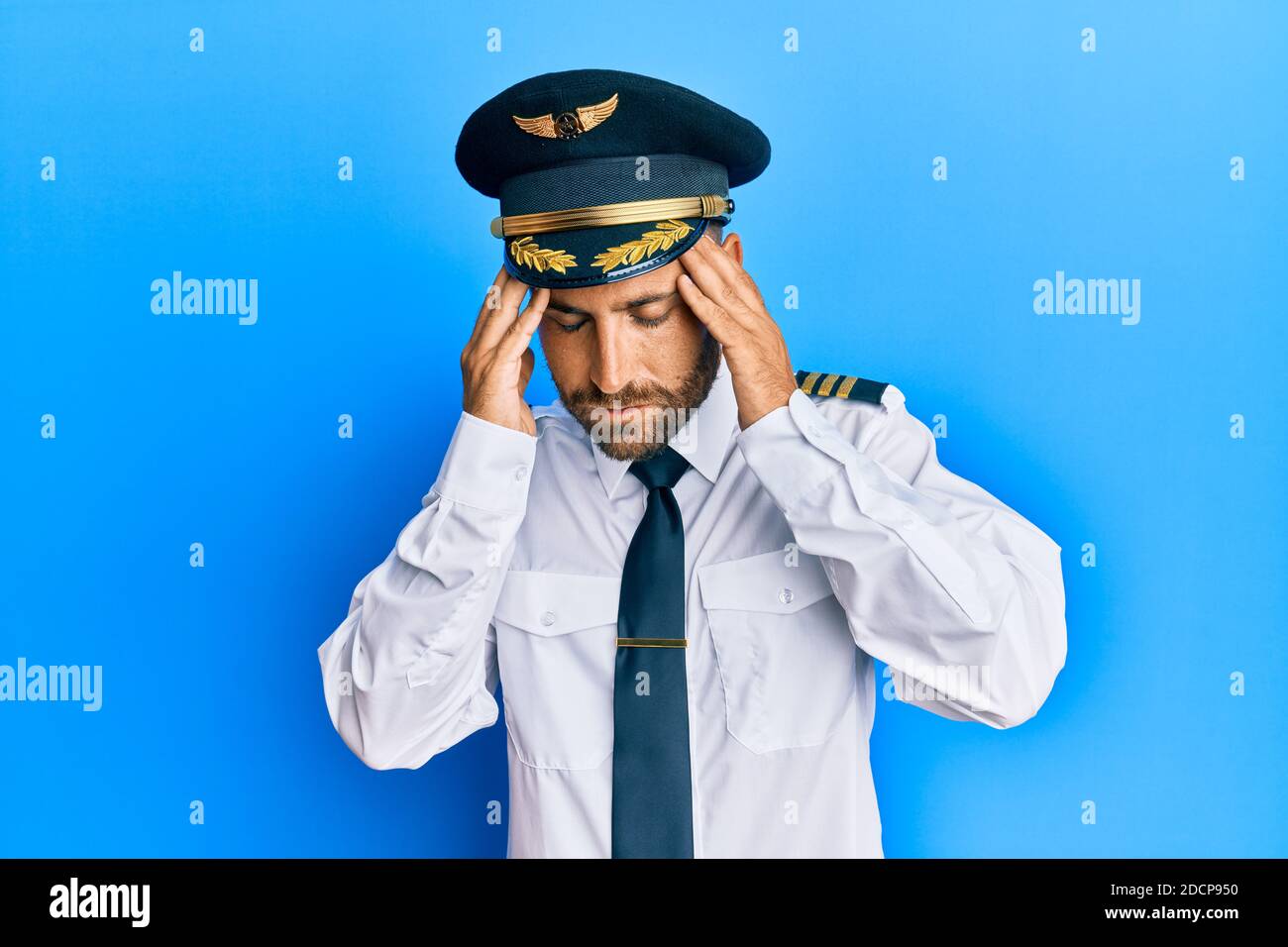 Handsome man with beard wearing airplane pilot uniform with hand on ...