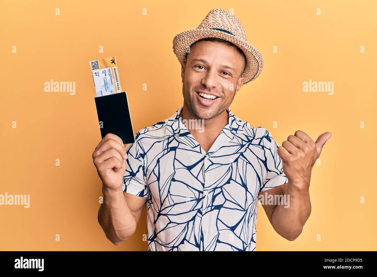 Handsome muscle man holding boarding pass and passport pointing thumb ...