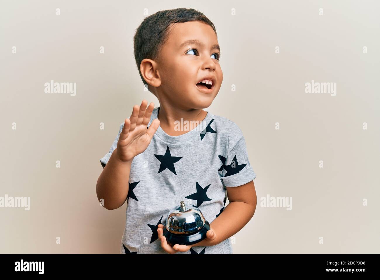 Adorable latin toddler smiling happy using receptionist ring bell over ...