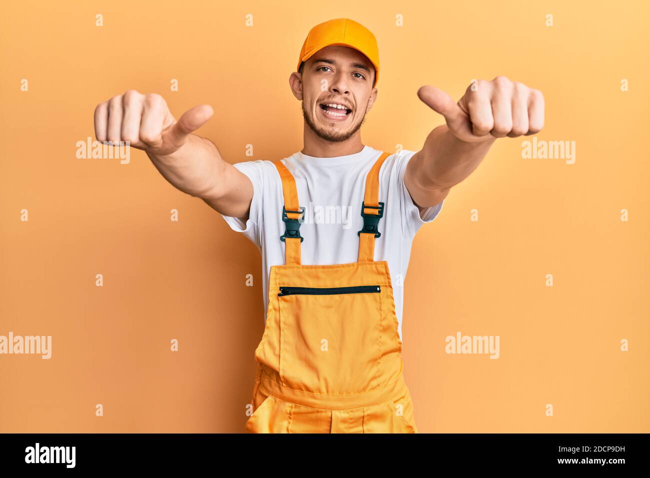 Young hispanic man wearing handyman uniform doing funny gesture with ...