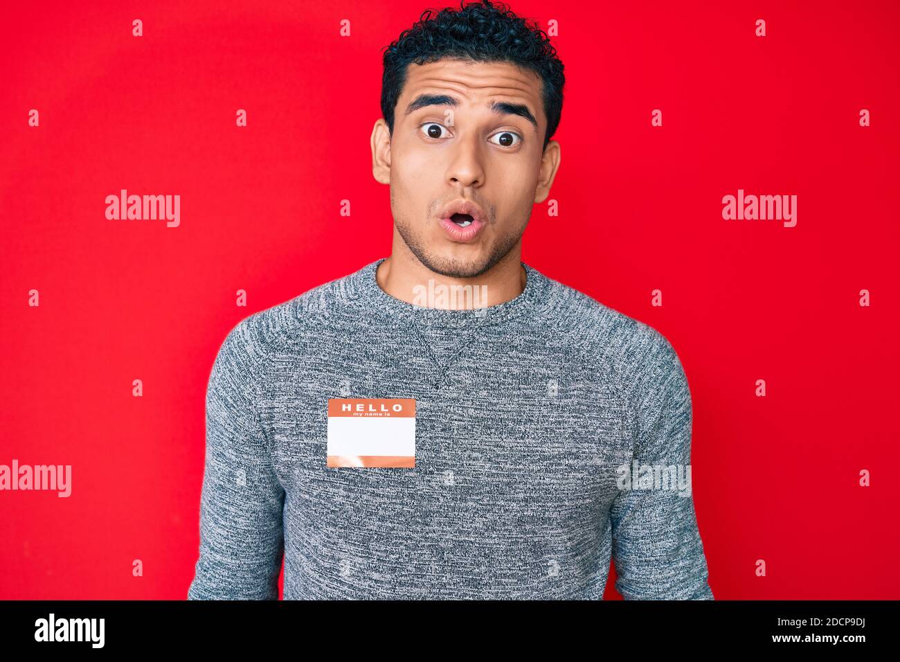 Young handsome hispanic man wearing hello my name is sticker ...