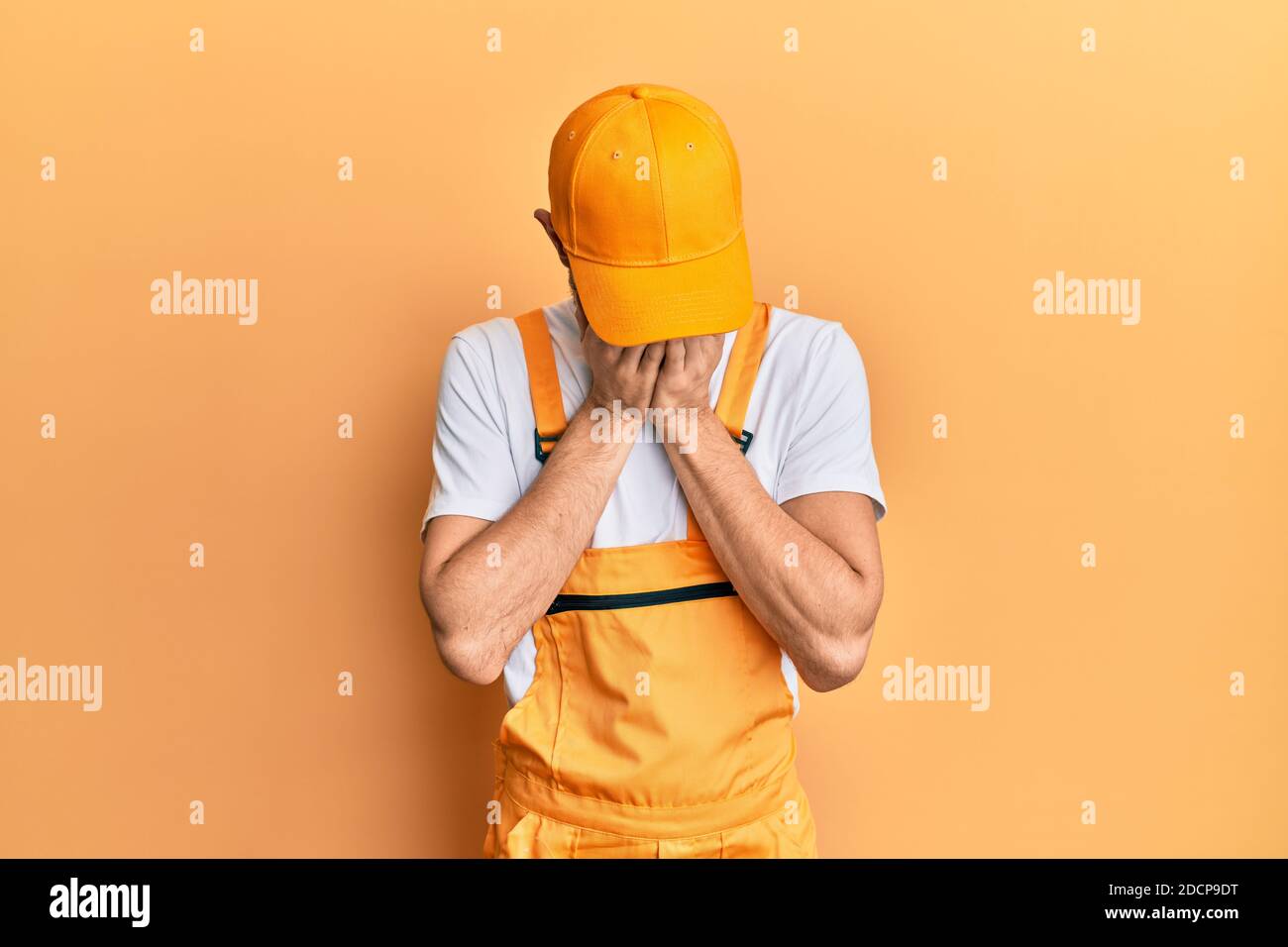 Young hispanic man wearing handyman uniform pointing aside worried and ...