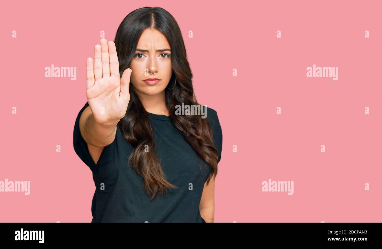 Beautiful brunette young woman wearing black shirt doing stop sing with ...