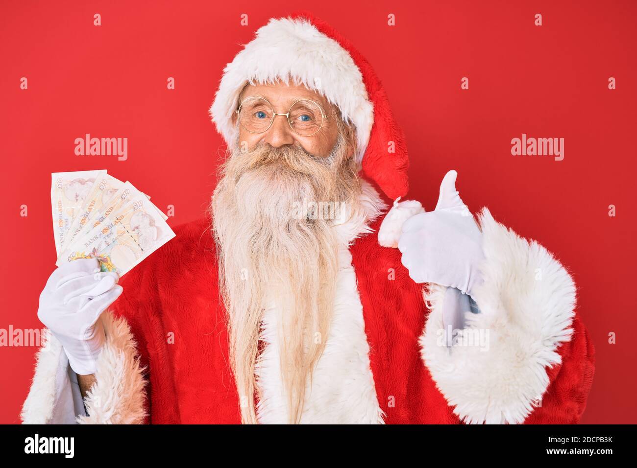 Old senior man with grey hair and long beard wearing santa claus ...
