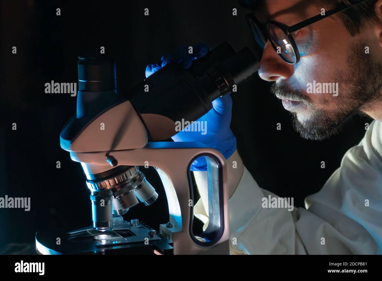 Scientist is looking in microscope in laboratory at night. Microbiology ...