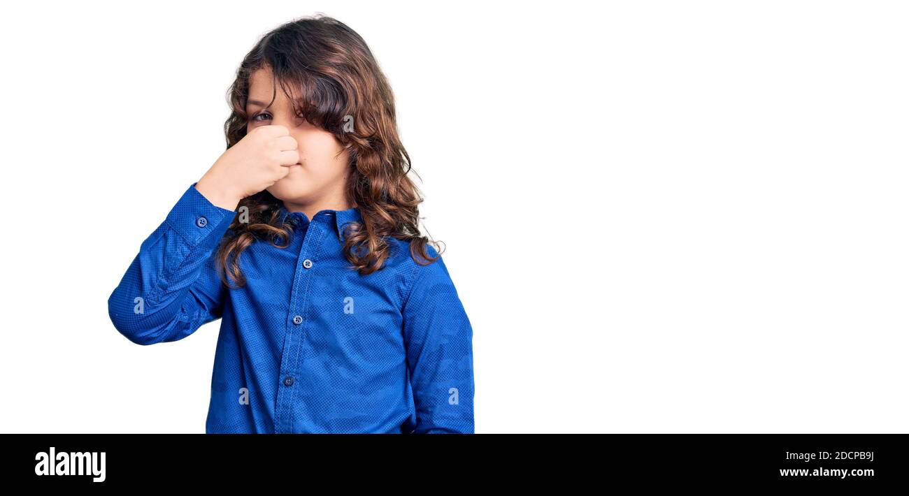 Cute child with long hair wearing casual clothes smelling something ...
