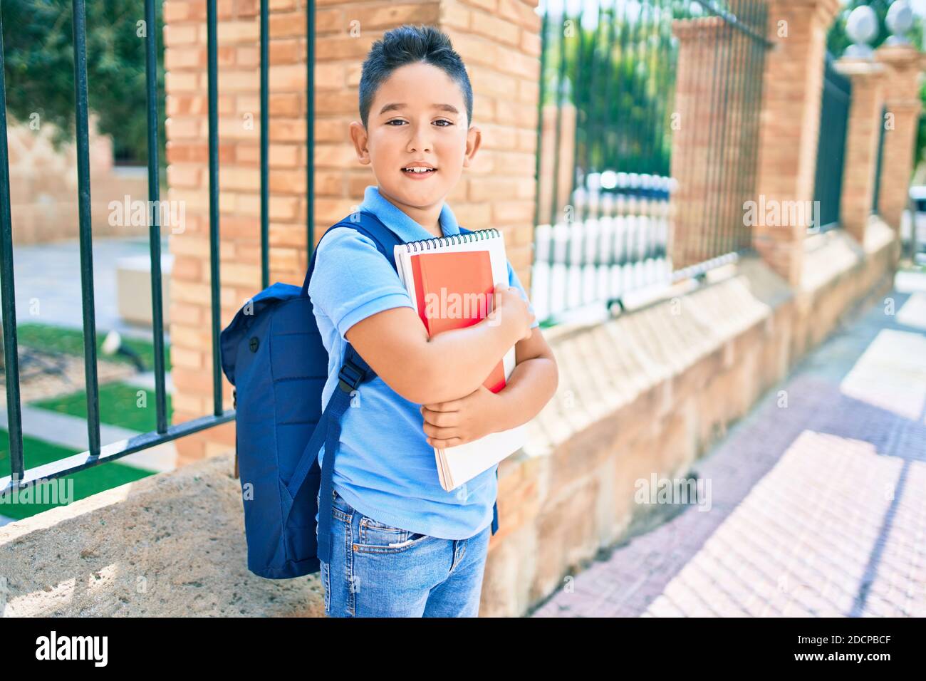 Adorable student boy smiling happy holding book at street of city Stock ...