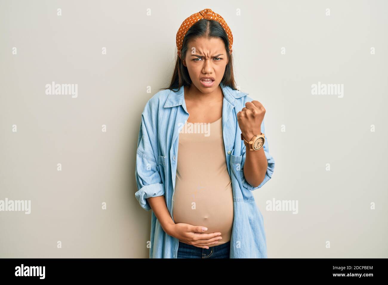 Beautiful hispanic woman expecting a baby, touching pregnant belly ...
