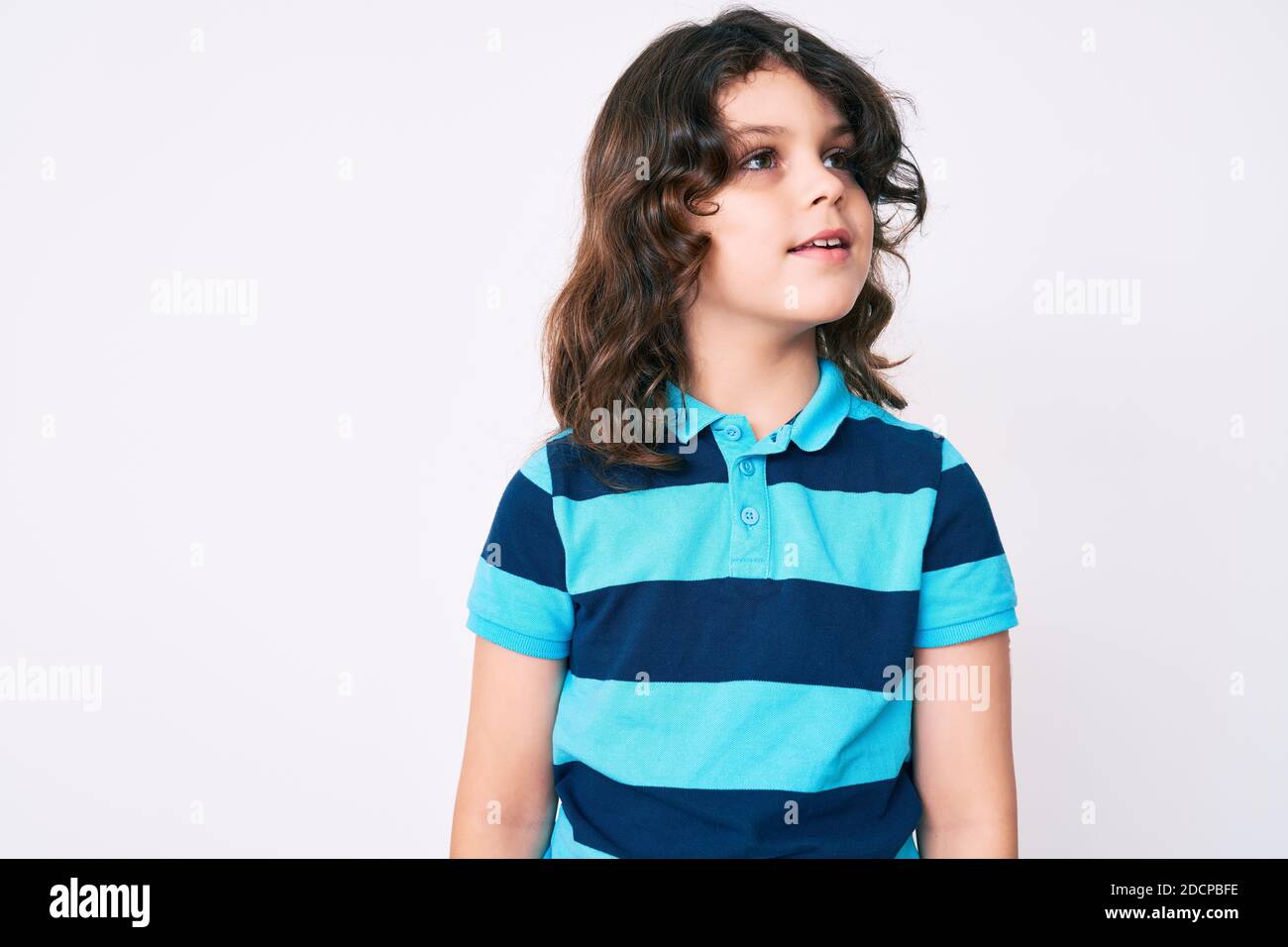 Cute hispanic child with long hair wearing casual clothes looking to ...