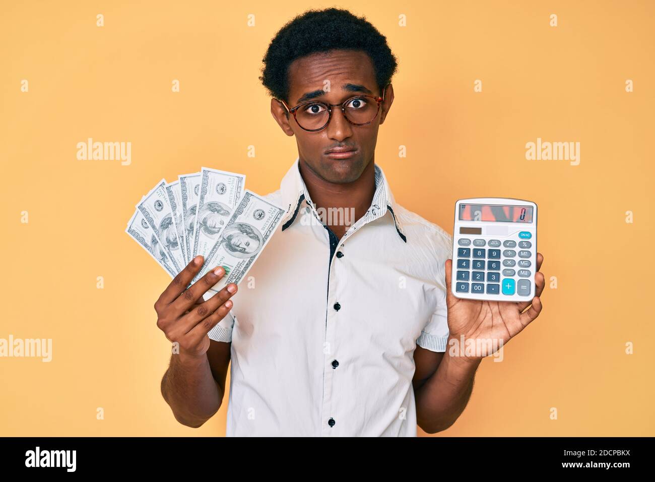 African handsome man holding dollars calculating savings depressed and ...