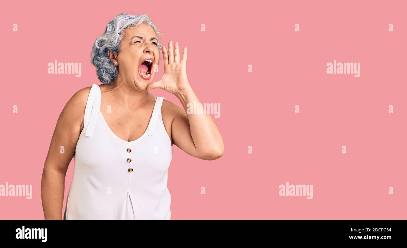 Senior woman with gray hair wearing casual clothes shouting and ...