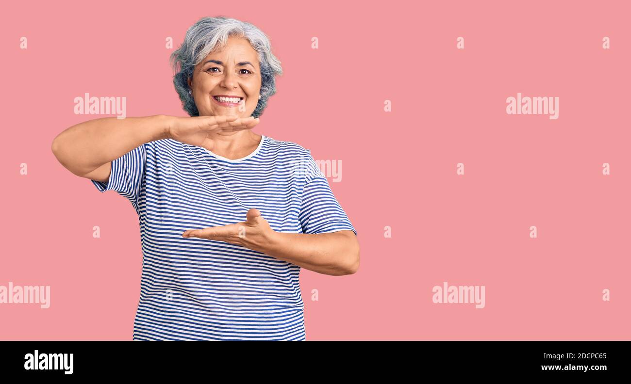 Senior woman with gray hair wearing casual striped clothes gesturing ...