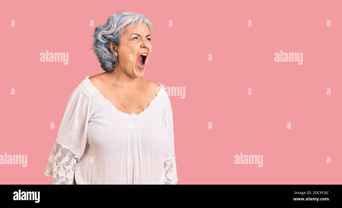 Senior woman with gray hair wearing bohemian style angry and mad ...