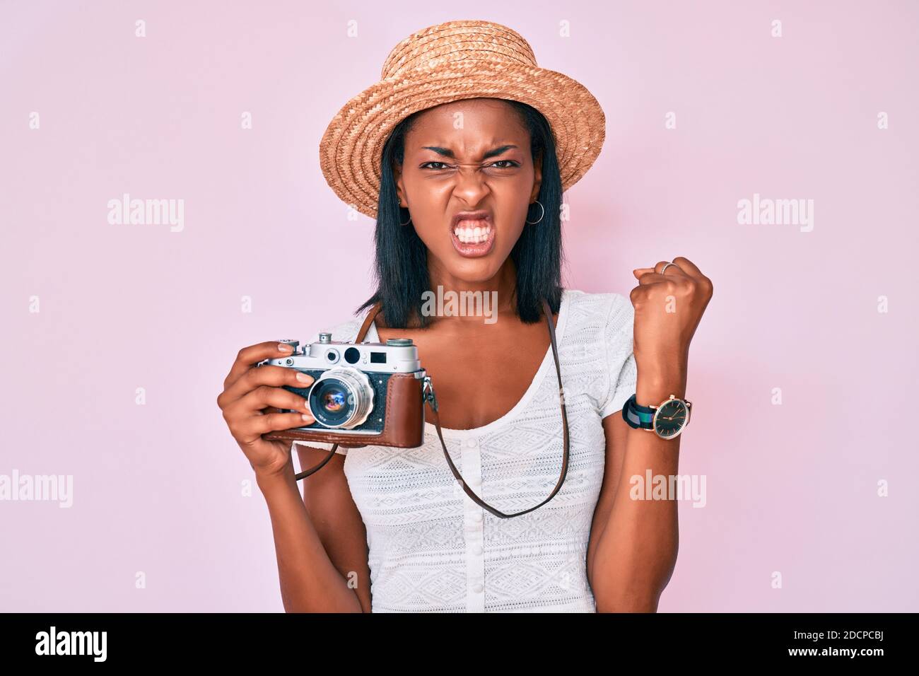 Young african american woman wearing summer hat holding vintage camera ...