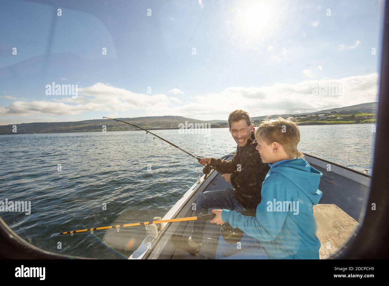 Through window side view of delighted father and son with rods fishing ...