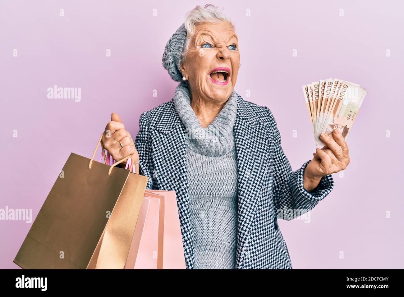 Senior grey-haired woman holding shopping bags and south korea won ...