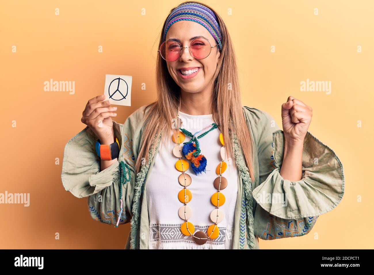 Young beautiful woman wearing hippie clothes holding peace reminder ...