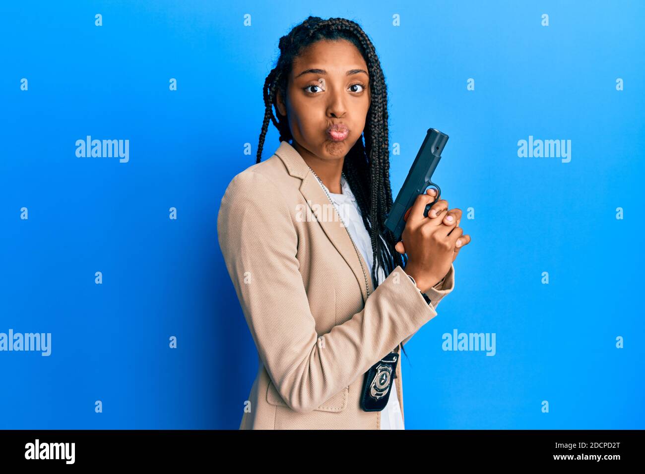 African American Police Woman Holding Gun Puffing Cheeks With Funny