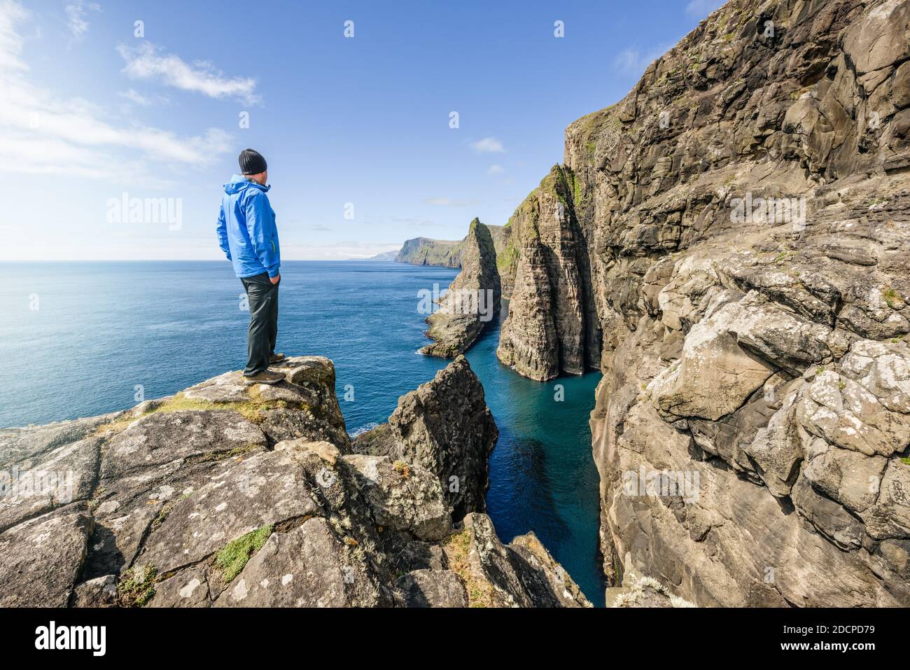 Side view of unrecognizable male explorer standing on rocky cliff and ...