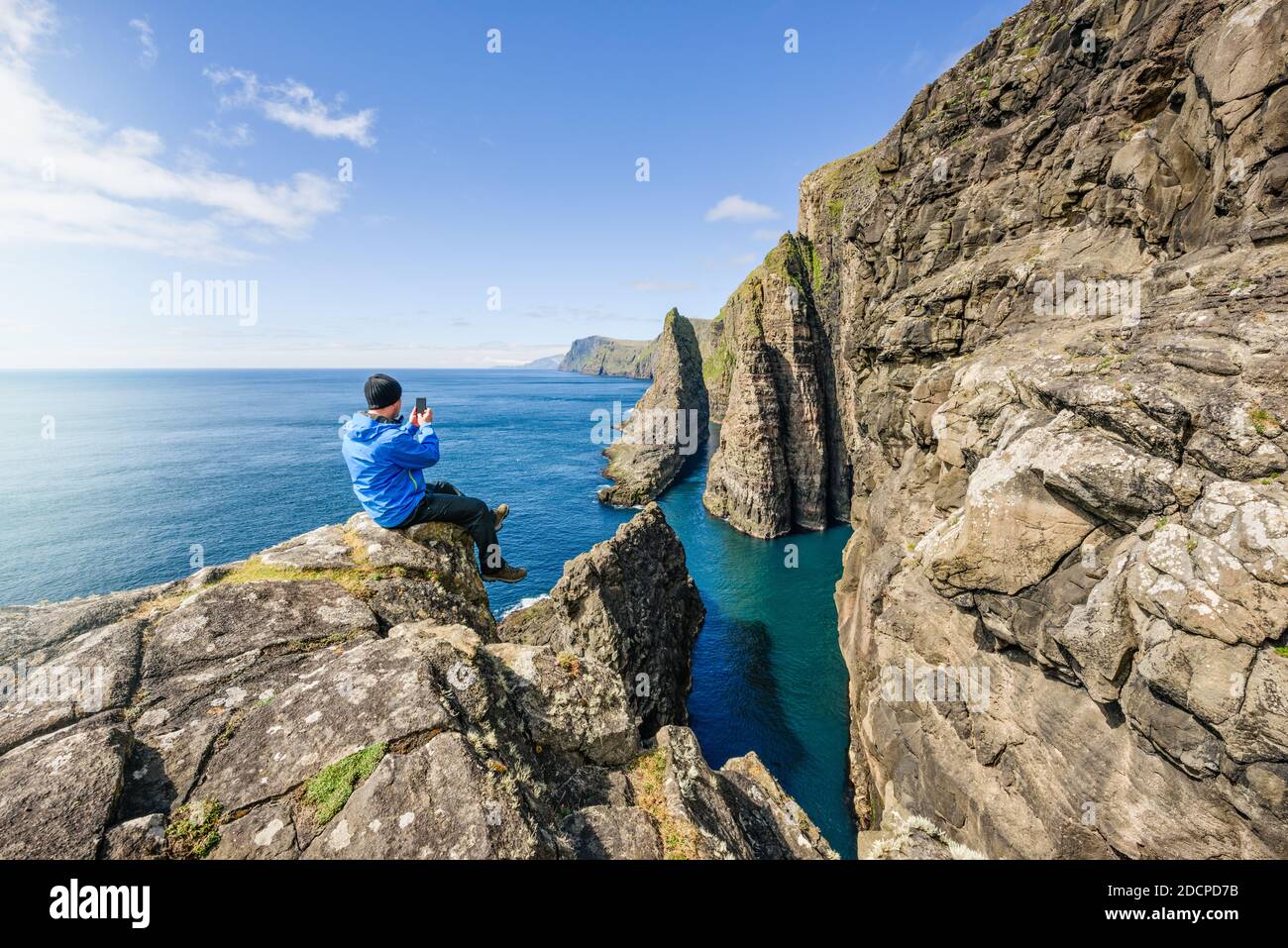 Side view of anonymous male traveler taking photo of cliff near sea ...