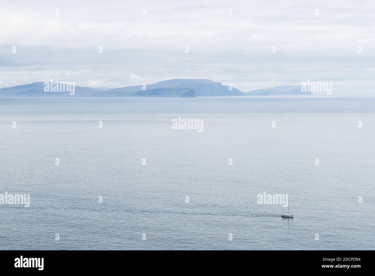 Aerial view of sailboat floating on sea water on background of mountain ...