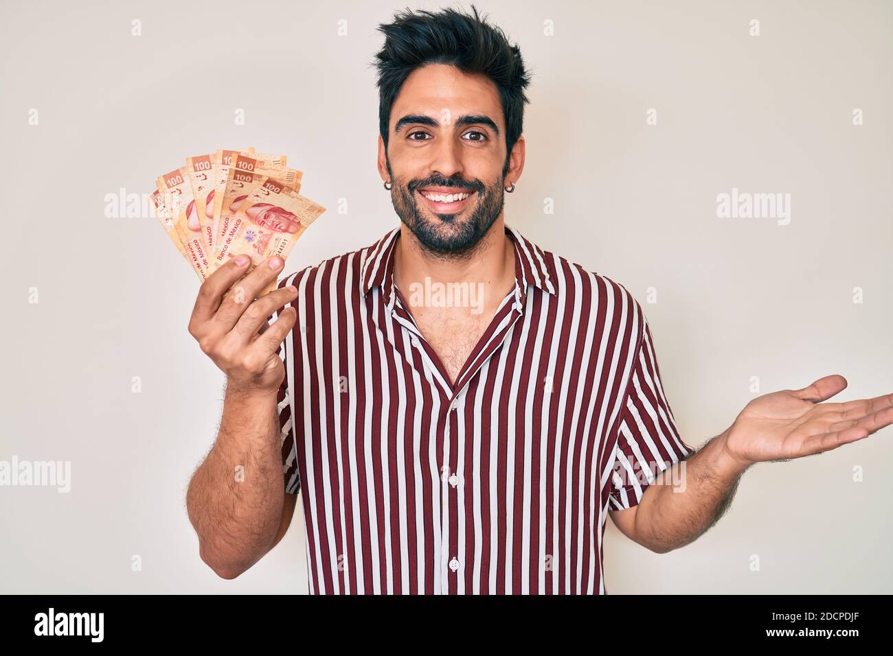 Handsome hispanic man with beard holding mexican pesos celebrating ...