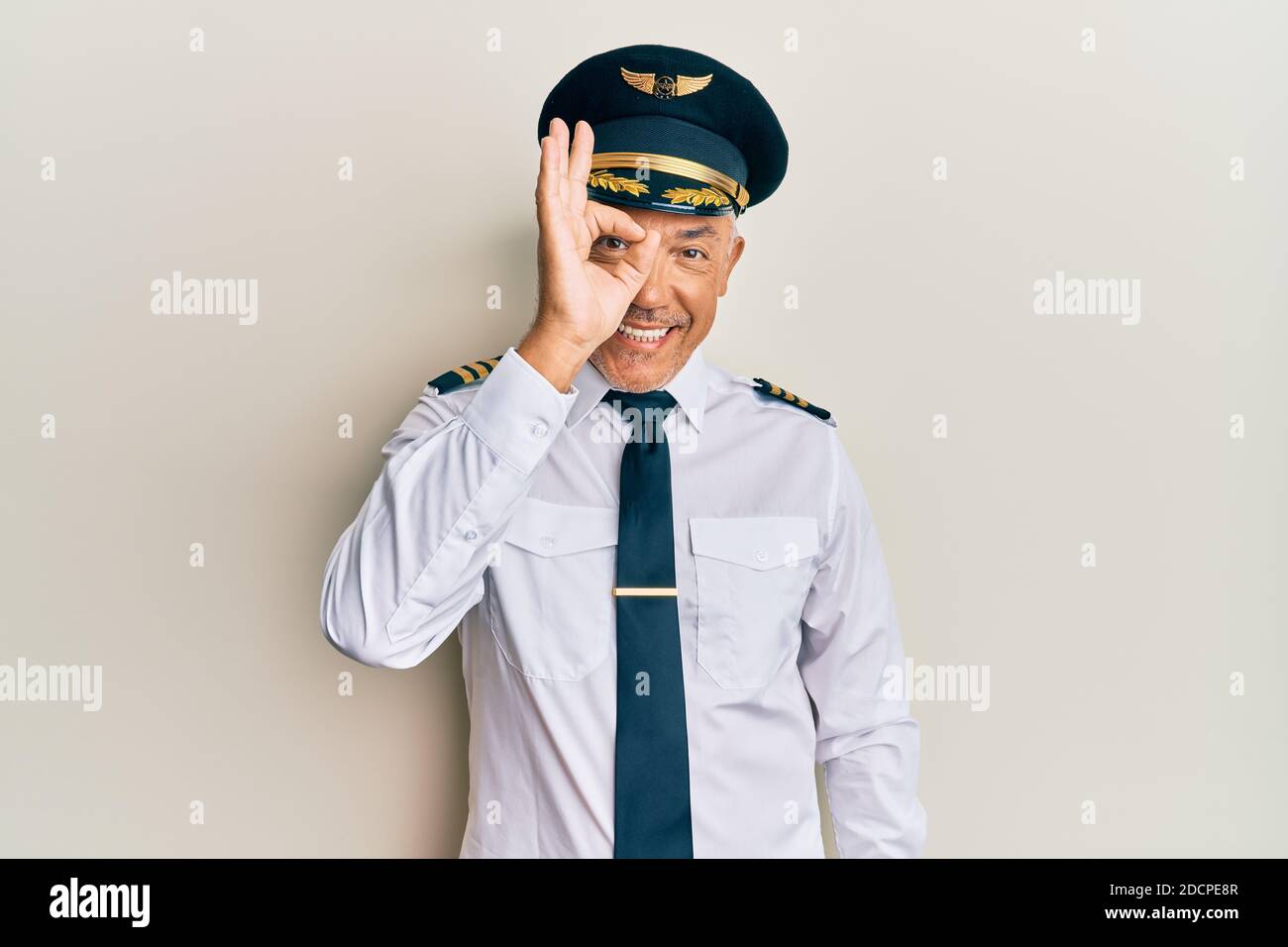 Handsome middle age mature man wearing airplane pilot uniform doing ok ...