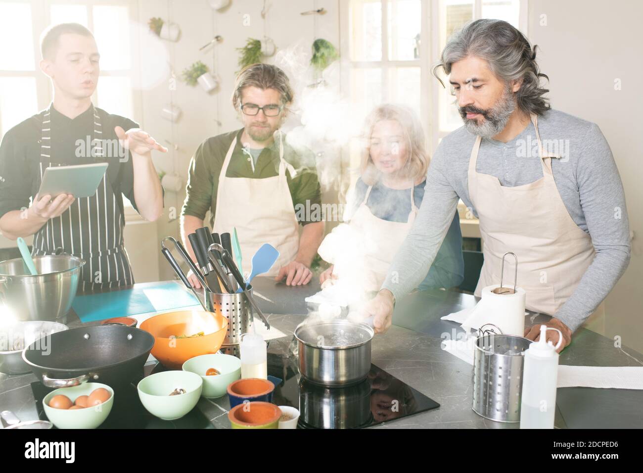 Group of young and mature people listening to male cooking coach with ...