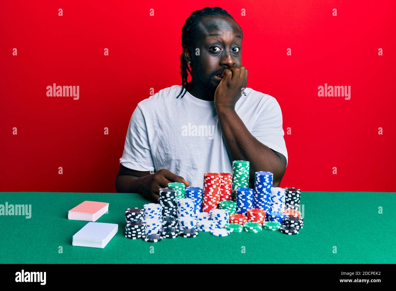 Handsome young black man sitting on the table with poker chips and ...