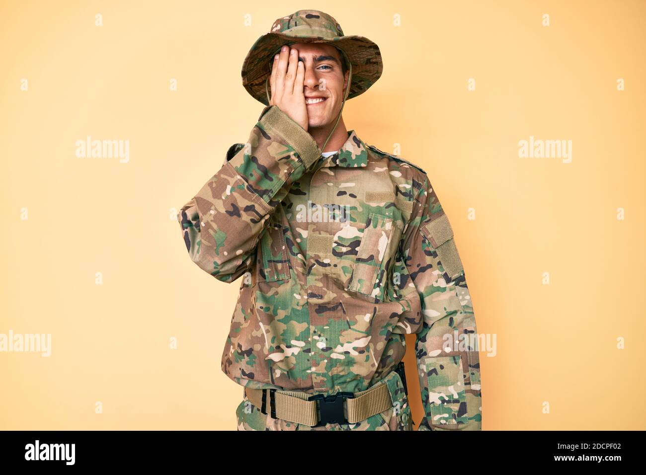 Young handsome man wearing camouflage army uniform covering one eye ...