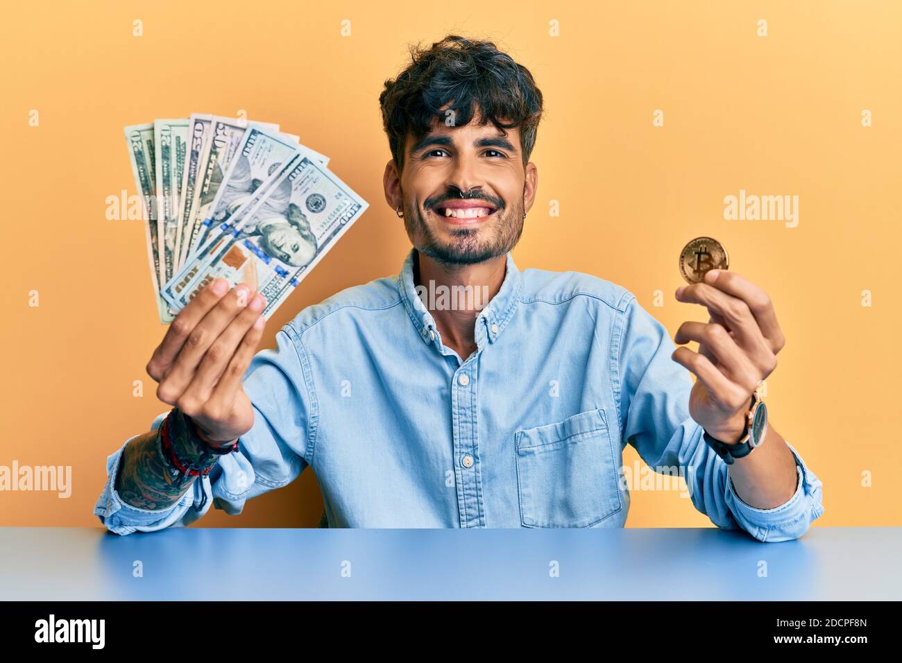 Young hispanic man holding dollars and bitcoin smiling with a happy and ...