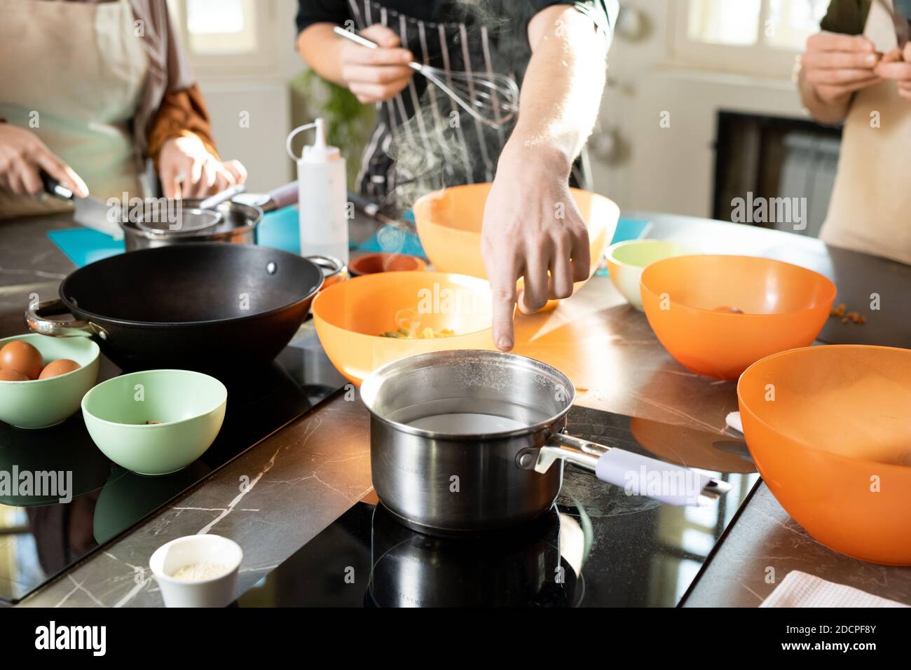 Hand of young cooking coach pointing at pan with warm water on electric ...