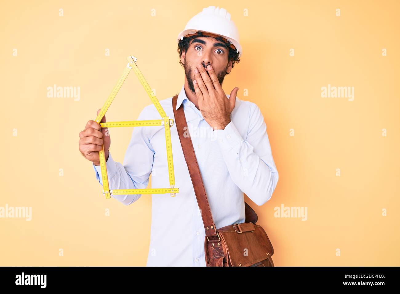 Handsome young man with curly hair and bear wearing architect hardhat ...