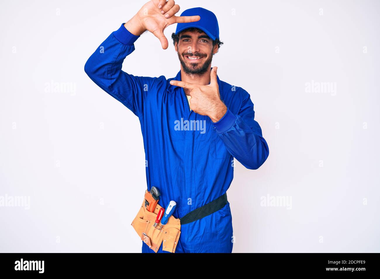 Handsome young man with curly hair and bear weaing handyman uniform ...