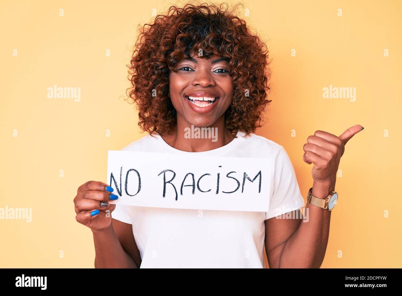 Young african american woman holding no racism banner pointing thumb up ...