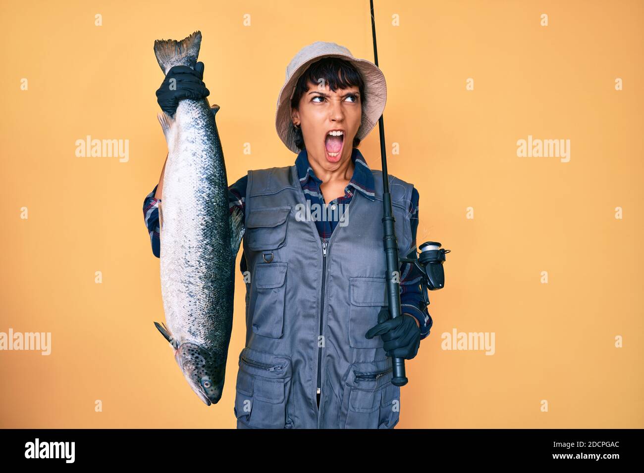 Beautiful brunettte fisher woman holding fishing rod and raw salmon ...